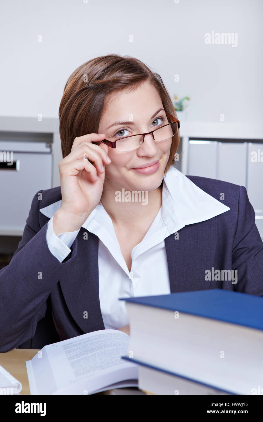 Smiling Business woman in the office looking over rim of her glasses ...