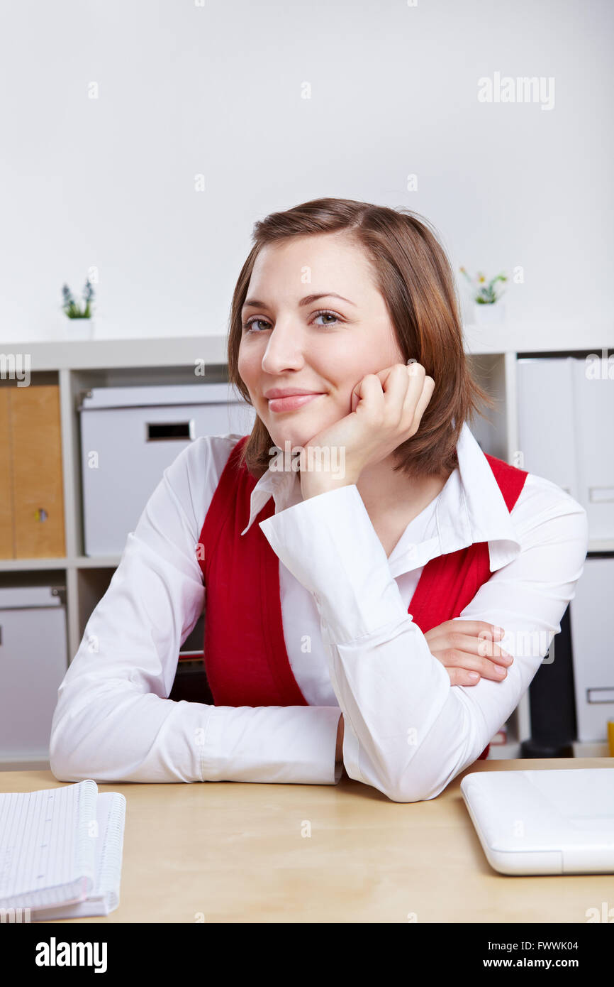 Attractive happy female manager sitting smiling at her desk in the ...