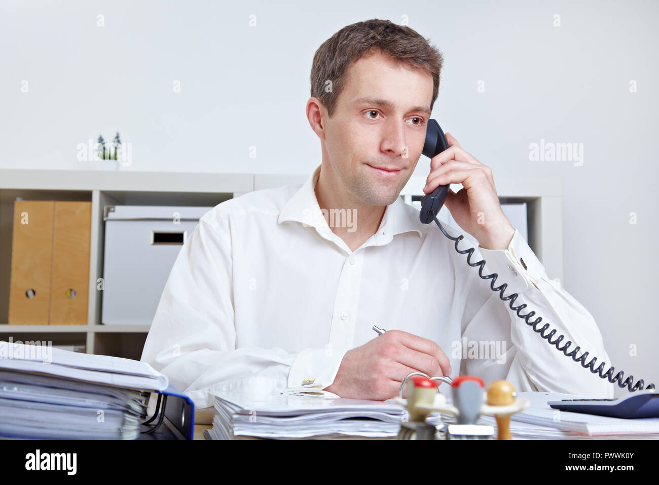 Business man making a call at his desk in the office Stock Photo - Alamy