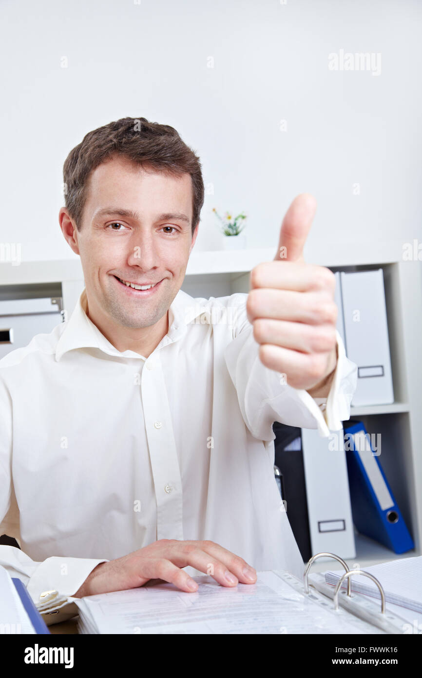 Smiling business manager holding his thumb up in the office Stock Photo ...