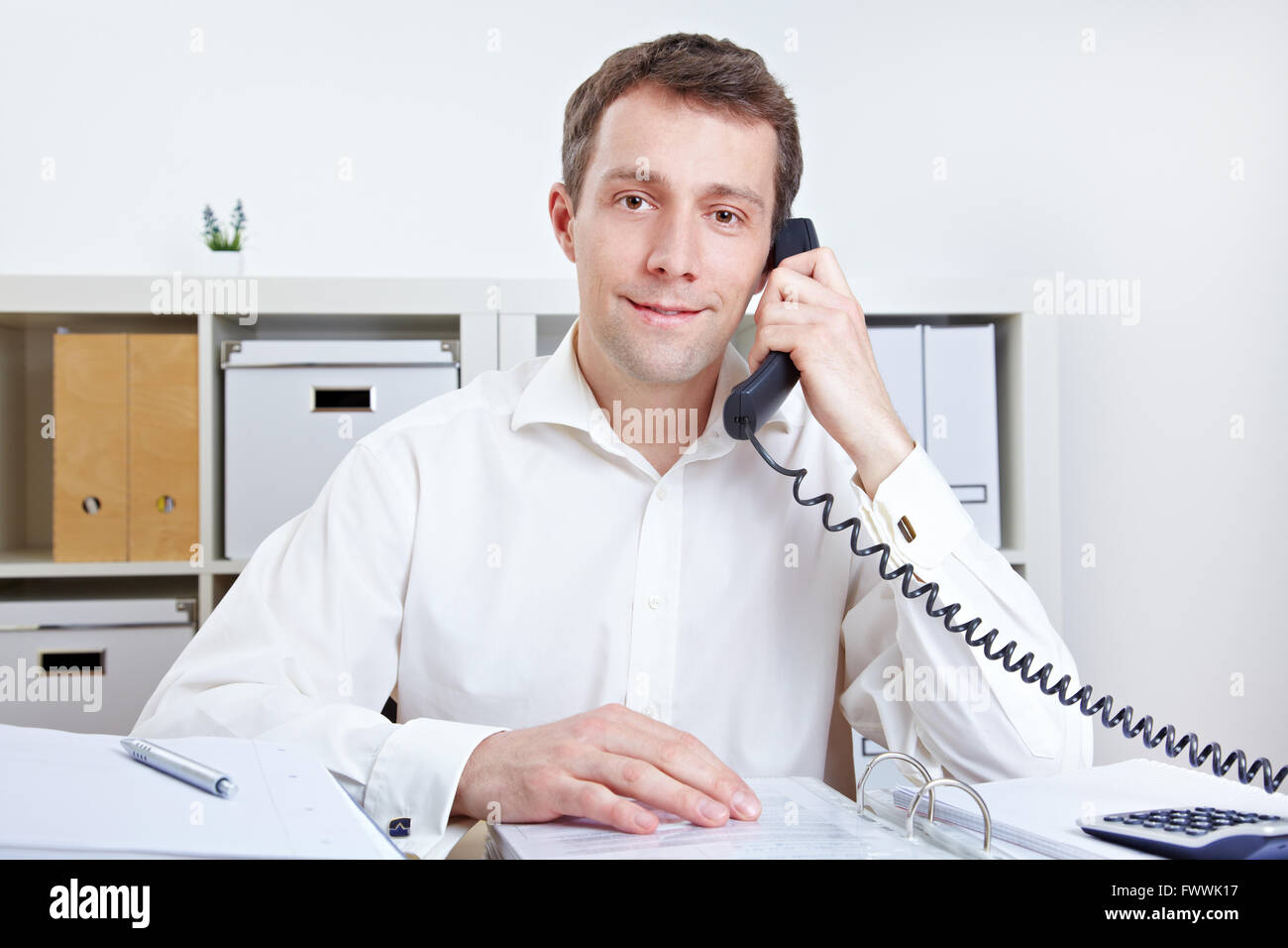 Smiling business man receiving a phone call in the office Stock Photo ...