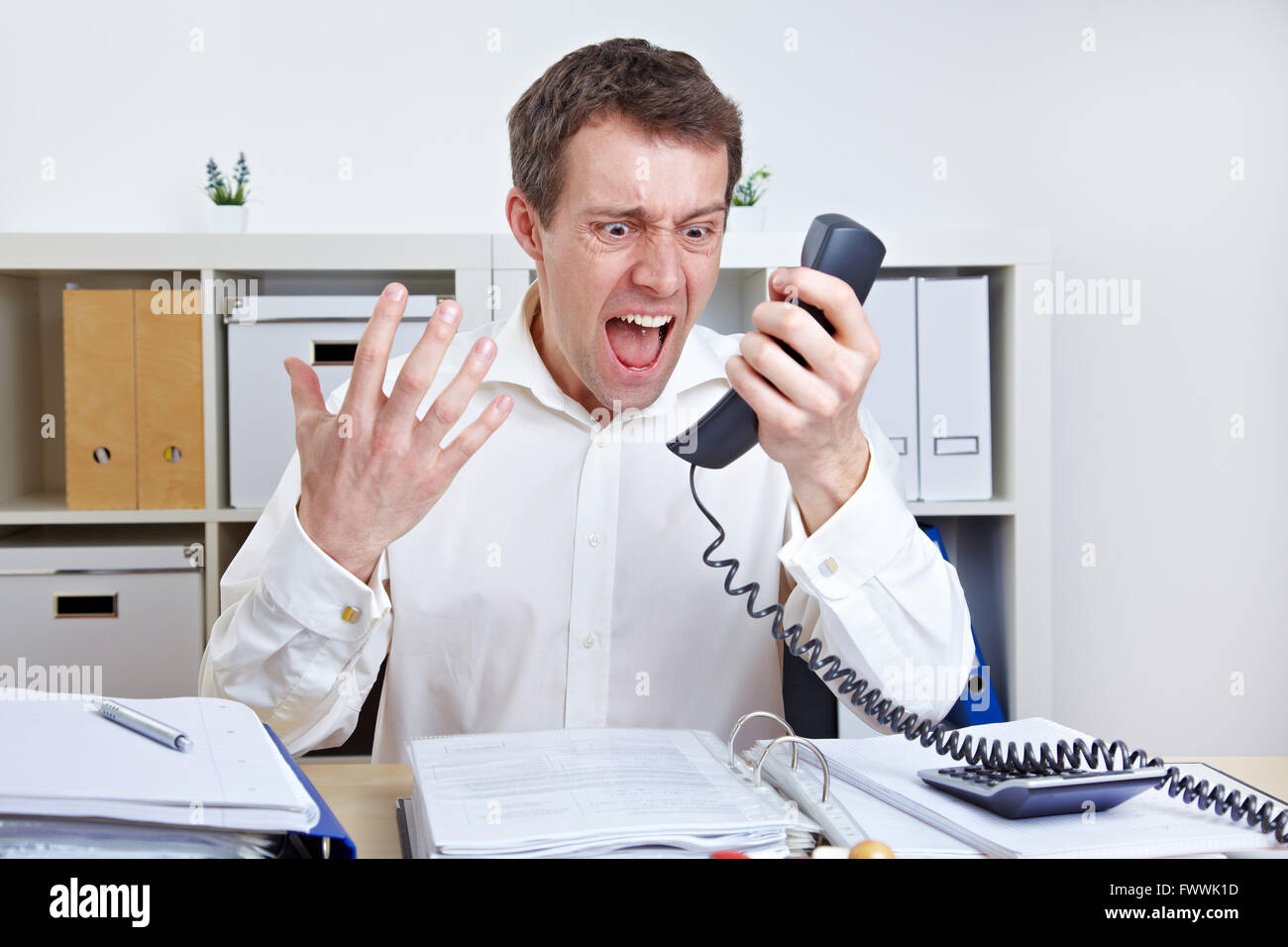 Angry business man screaming at phone in his office Stock Photo - Alamy