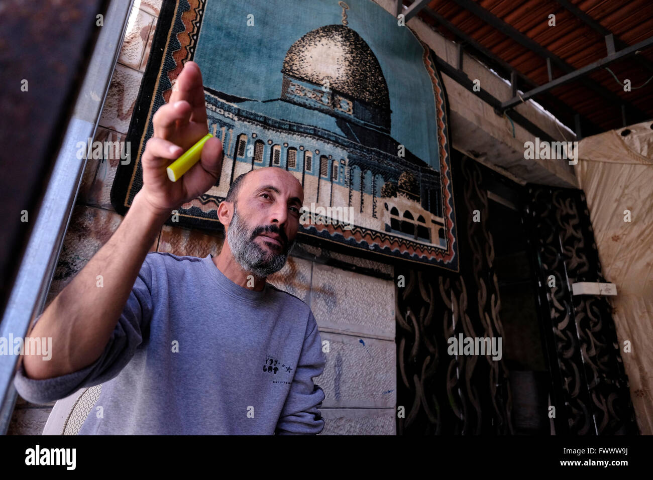 A Palestinian man sits in front of a rug depicting Dome of the rock in ...