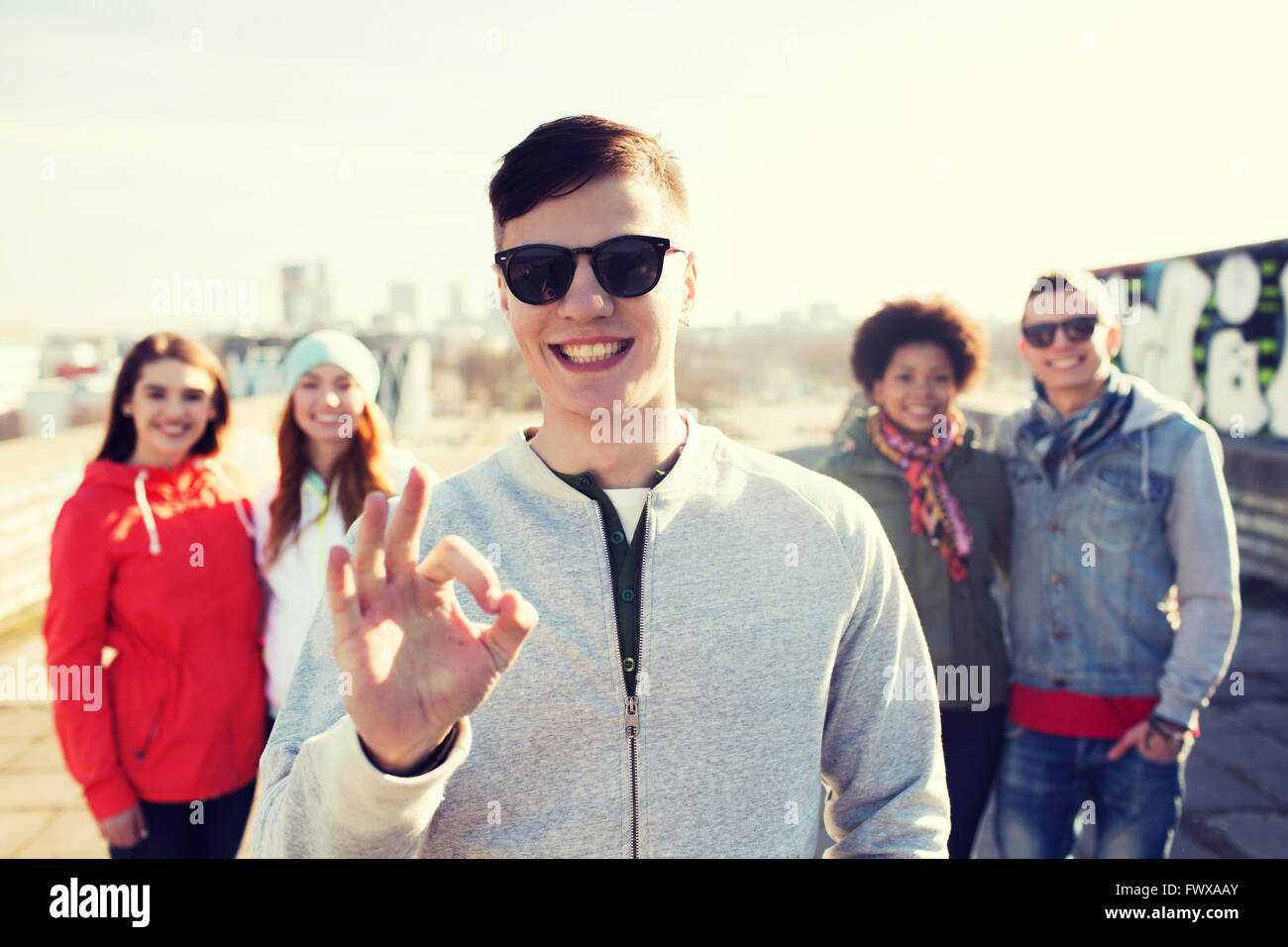 happy teenage friends showing ok sign on street Stock Photo - Alamy