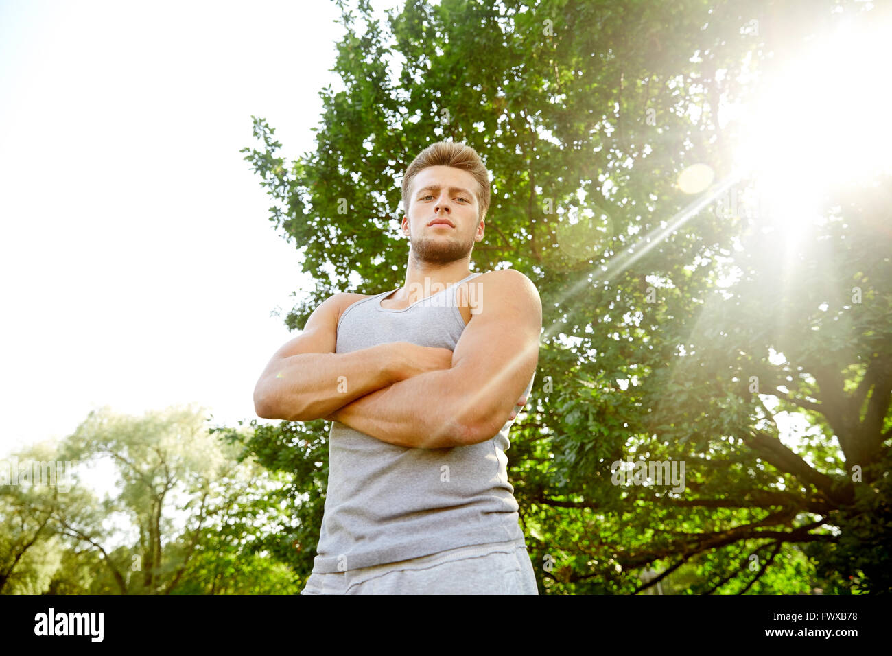 sporty young man with crossed arms at summer park Stock Photo - Alamy