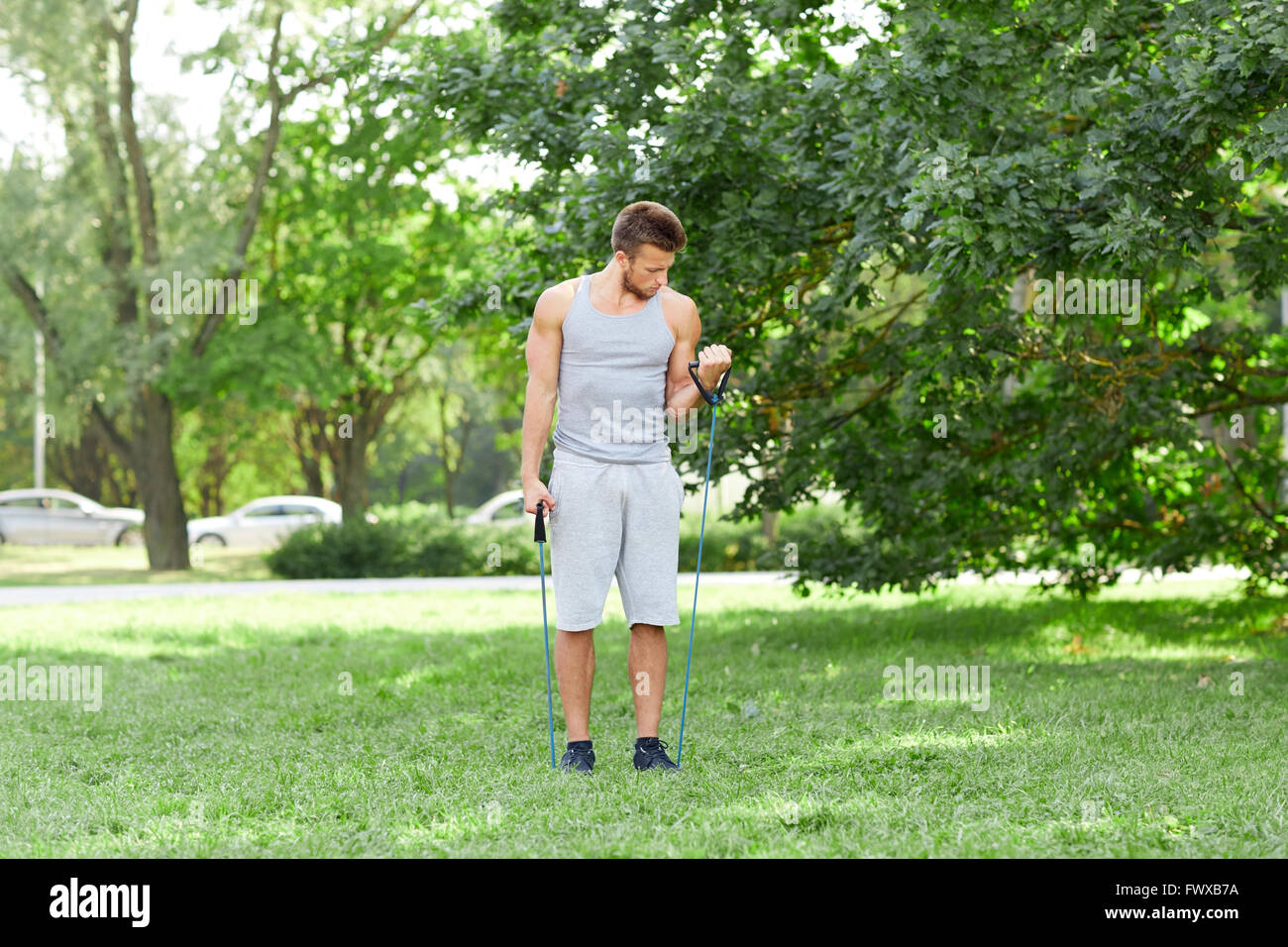 young man exercising with expander in summer park Stock Photo - Alamy