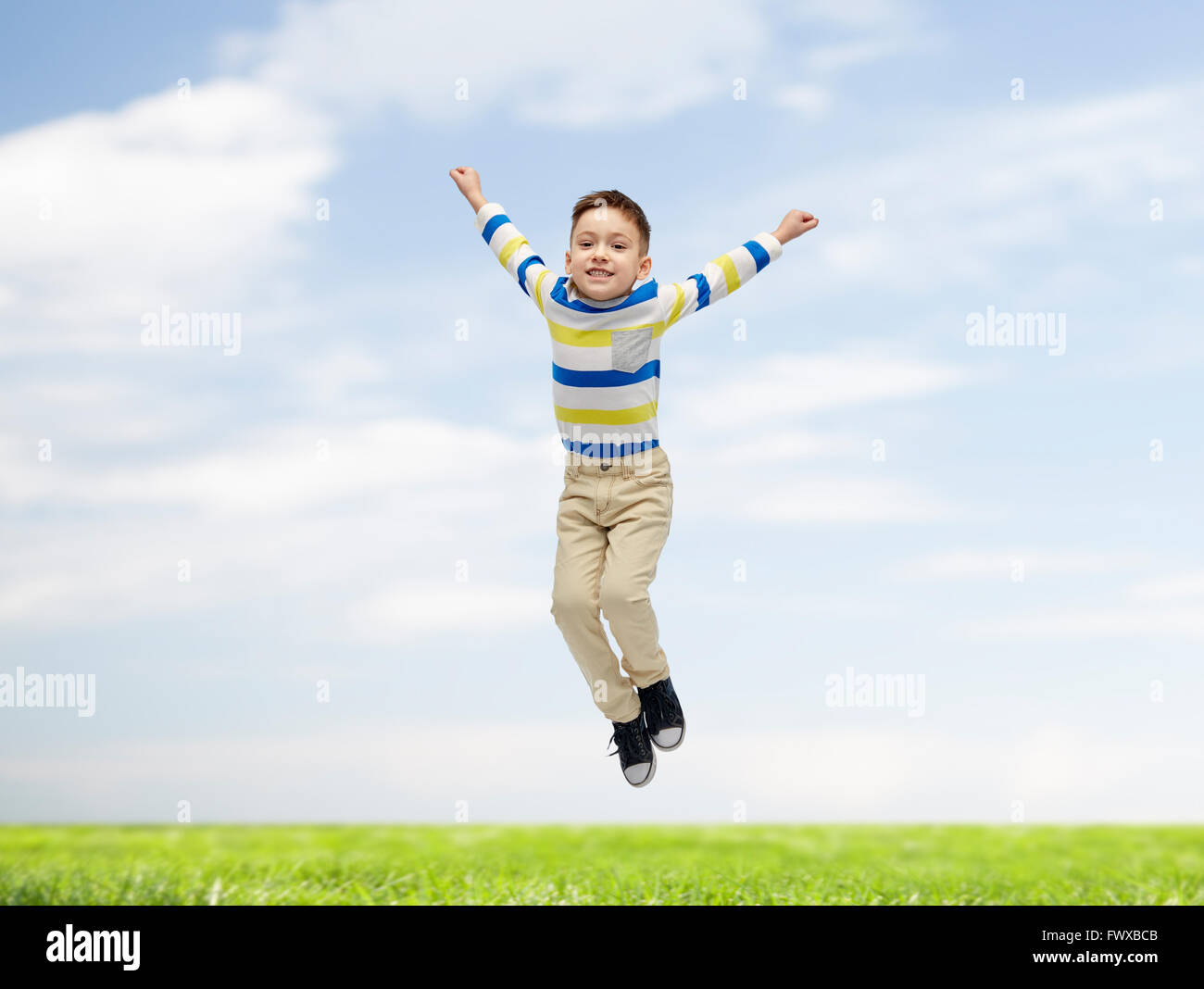 happy little boy jumping over blue sky and grass Stock Photo - Alamy