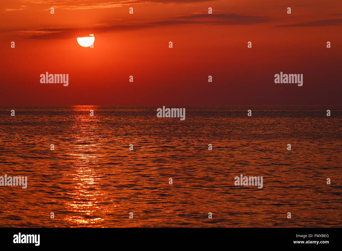 red sunset over the water. the rays of the setting sun reflected on the ...