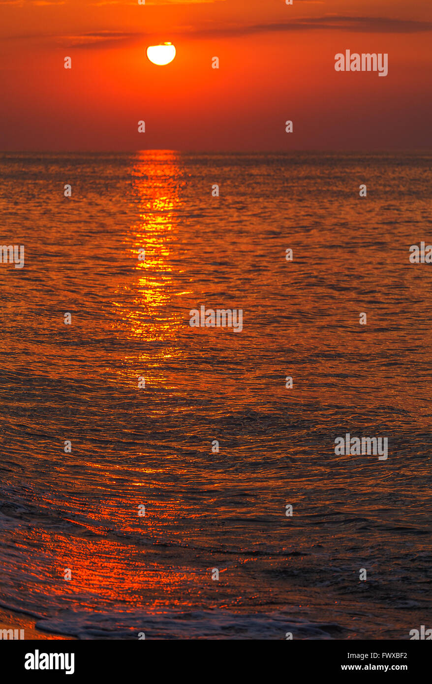 red sunset over the water. the rays of the setting sun reflected on the ...