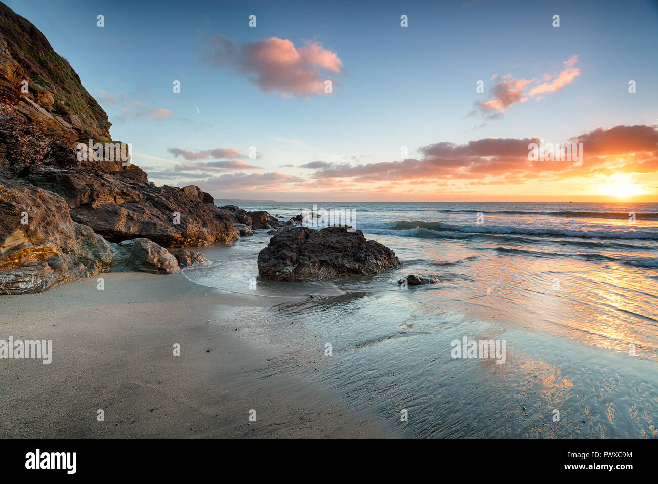 Stunning sunrise over rocks at low tide on the beach at Pentewan on the ...