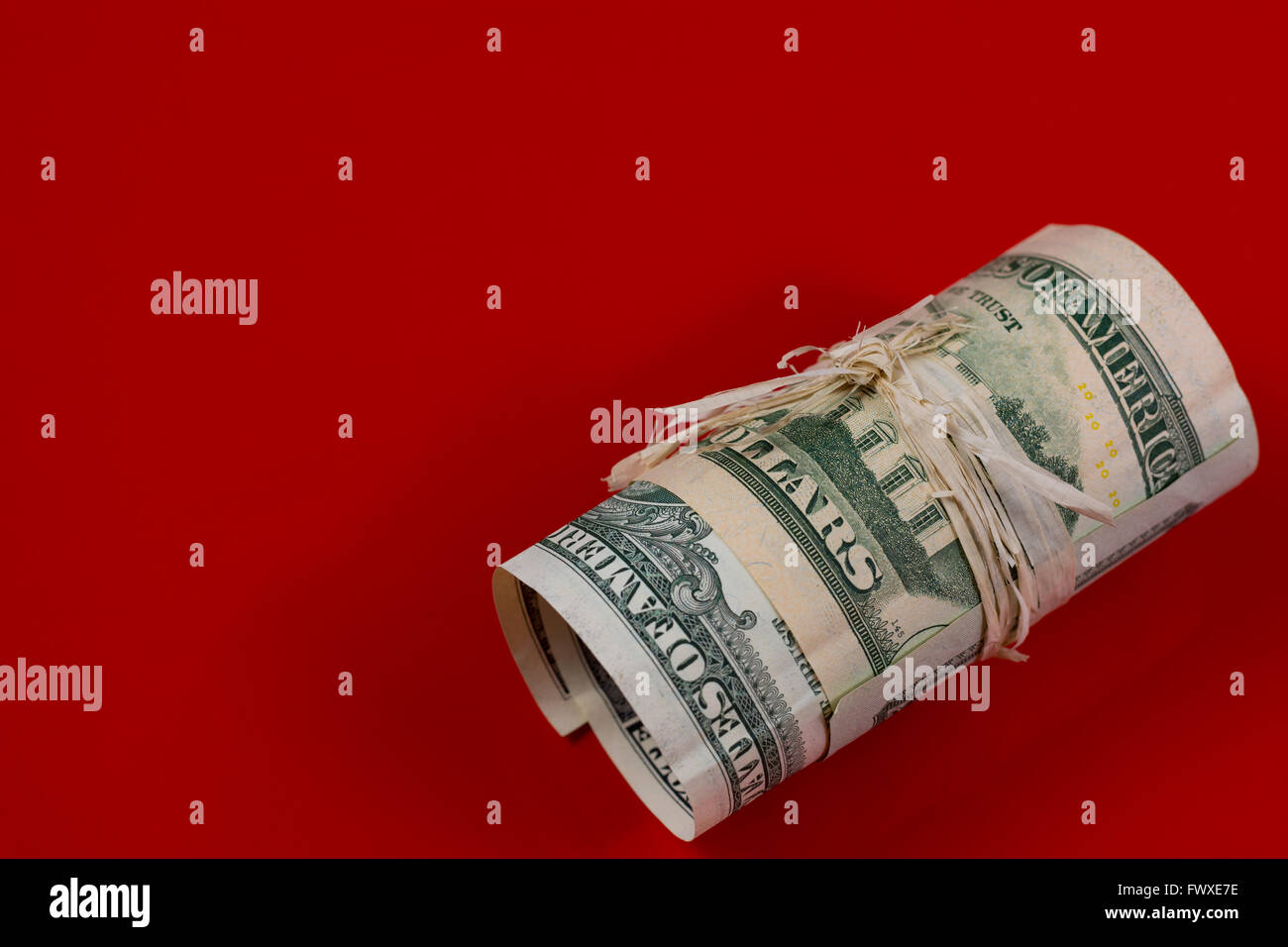 US dollars cash roll on red background Stock Photo - Alamy