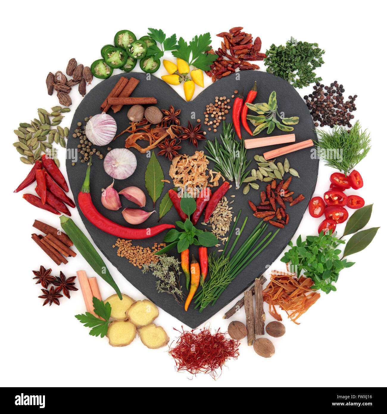 Herb and spice ingredients on a heart shaped slate and loose over white ...