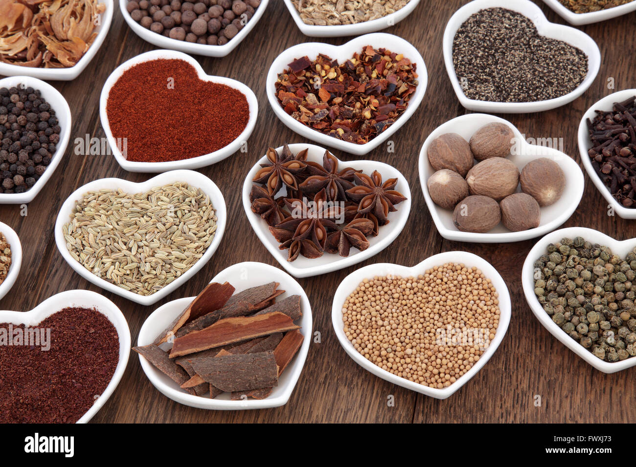 Spice selection in heart shaped porcelain dishes over old oak ...