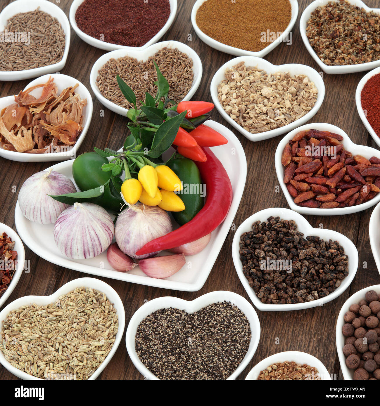 Herb and spice ingredients in a heart shaped porcelain dishes over old ...