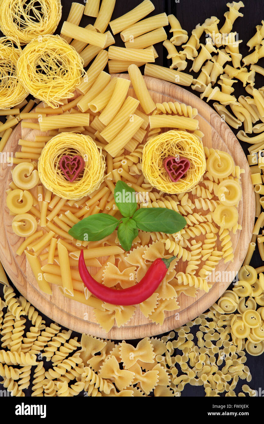 Pasta smiley face abstract background on a wooden board Stock Photo - Alamy
