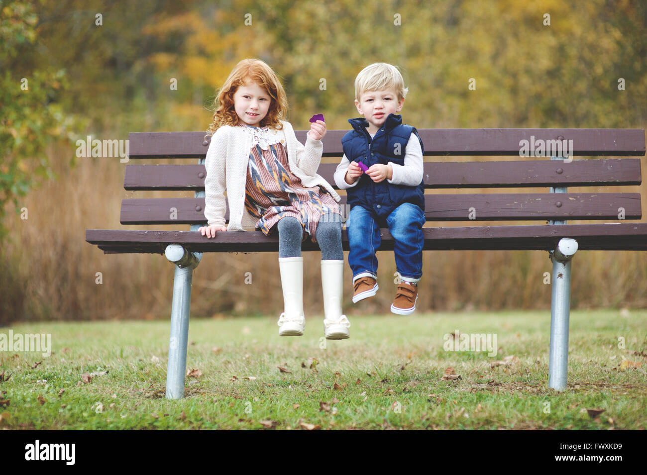 Brother and sister sitting on a park bench Stock Photo - Alamy