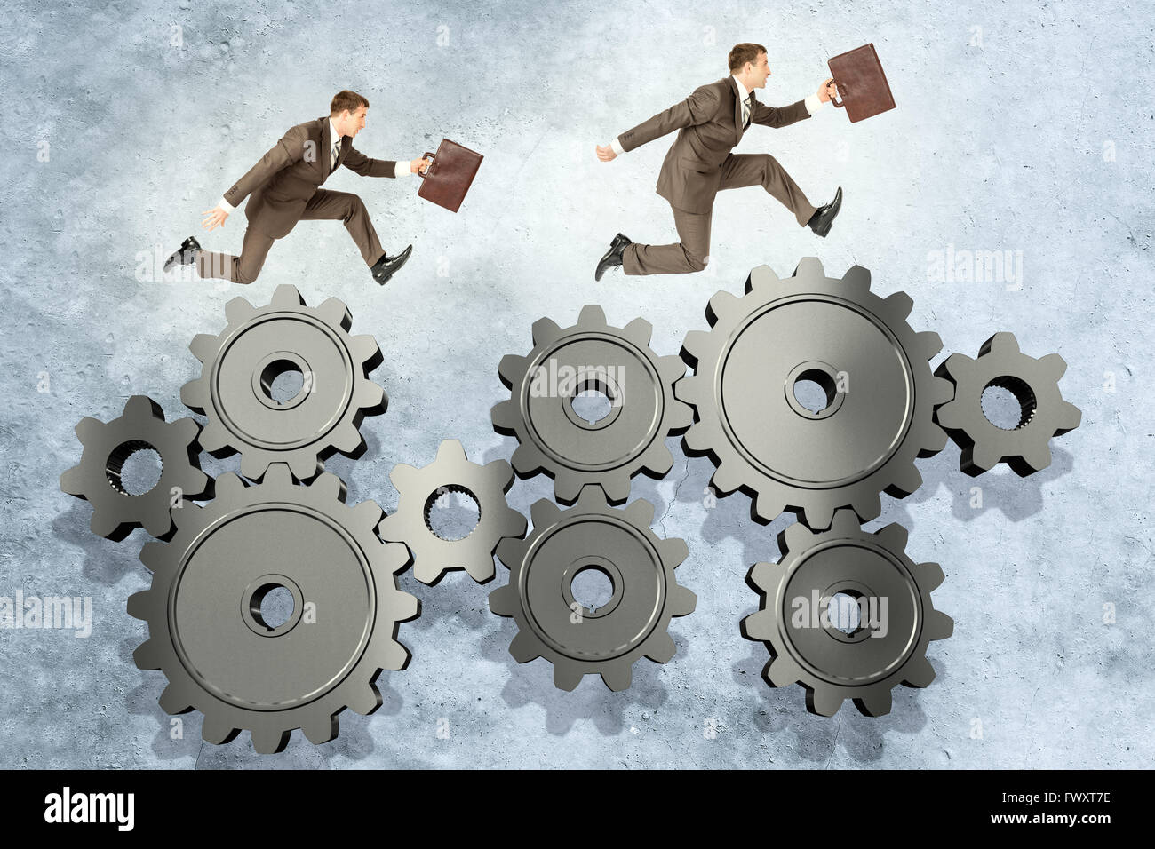Two businessmen running on wheel gears Stock Photo - Alamy