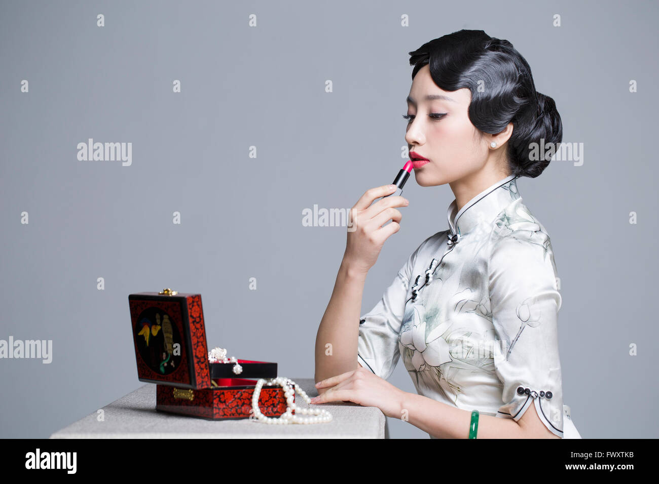 Young beautiful woman in traditional cheongsam applying lipstick Stock ...