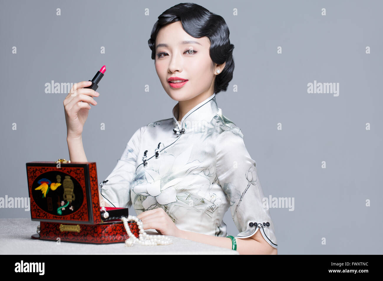 Young beautiful woman in traditional cheongsam holding a lipstick Stock ...