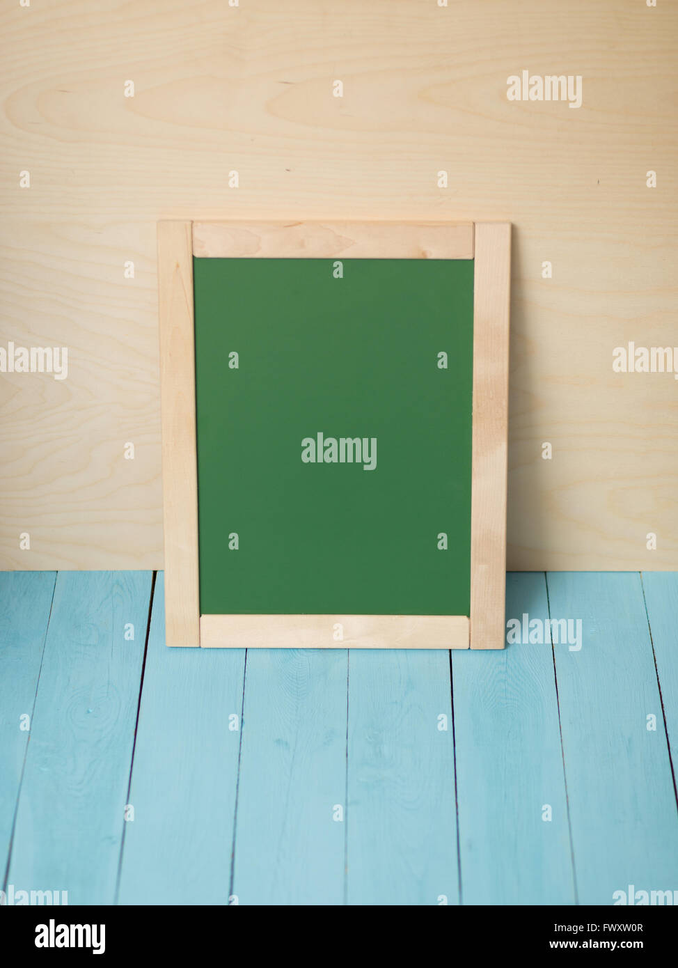 Empty green board standing near wooden wall Stock Photo - Alamy