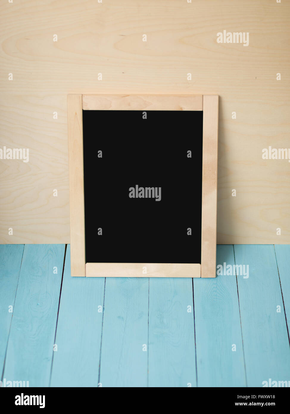 Empty black board standing near wooden wall Stock Photo - Alamy