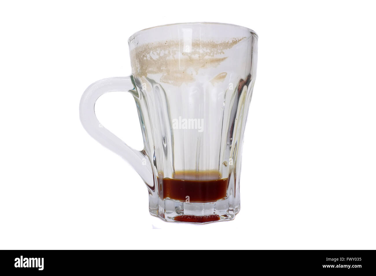 A nearly empty glass coffee cup photographed against a white background ...