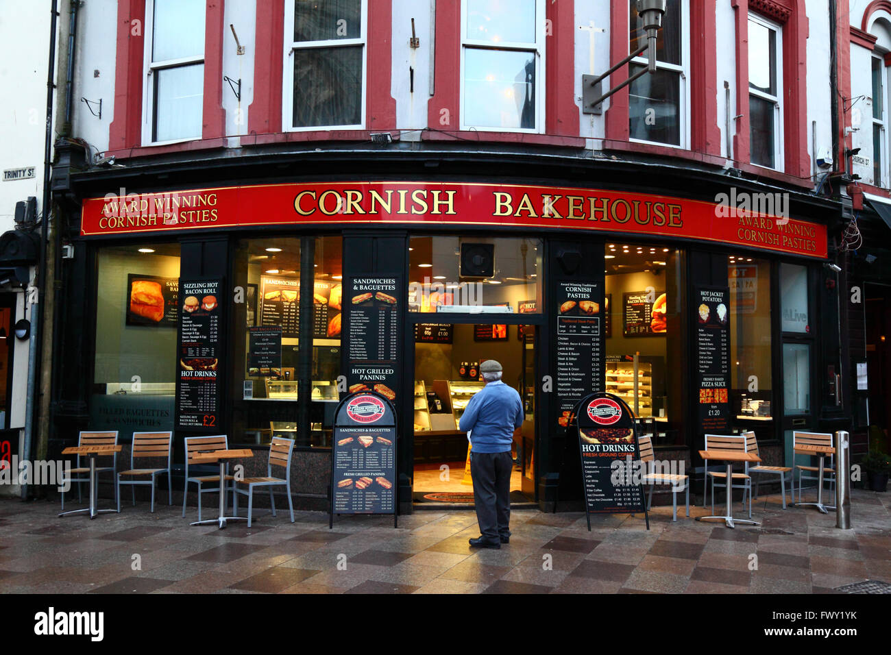 Man standing outside Cornish Bakehouse bakery / cafe looking at menu ...