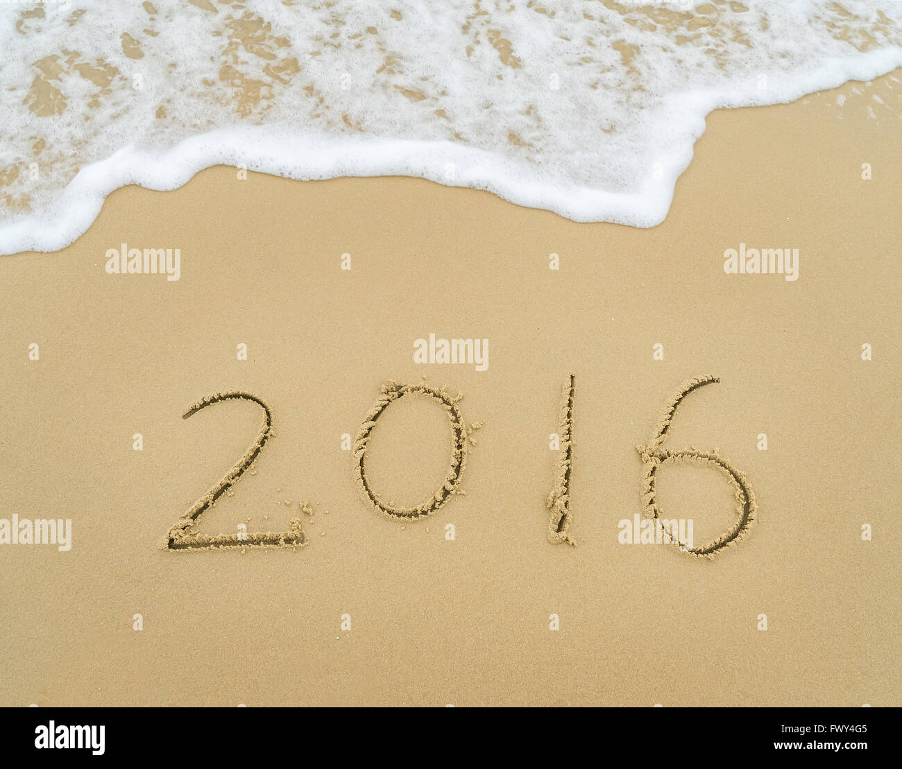 Year 2016 hand written on the white sand in front of the sea Stock ...
