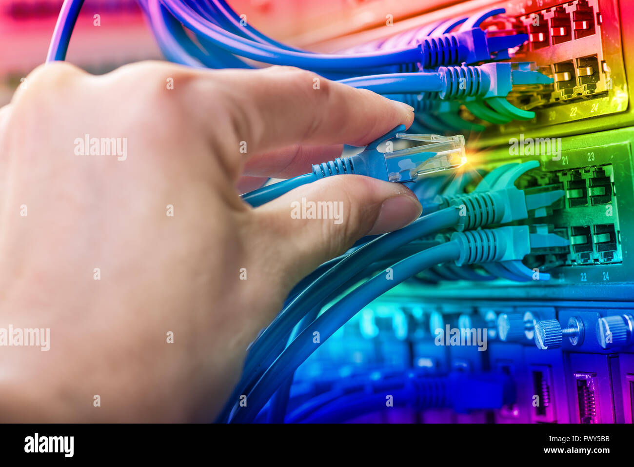 man working in network server room with fiber optic hub for digital ...