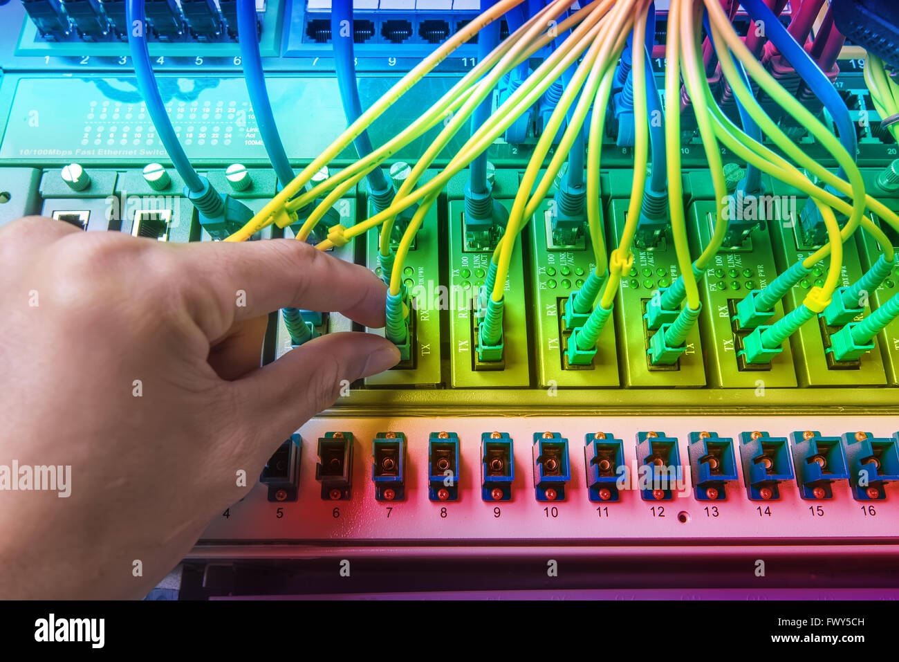 man working in network server room with fiber optic hub for digital ...