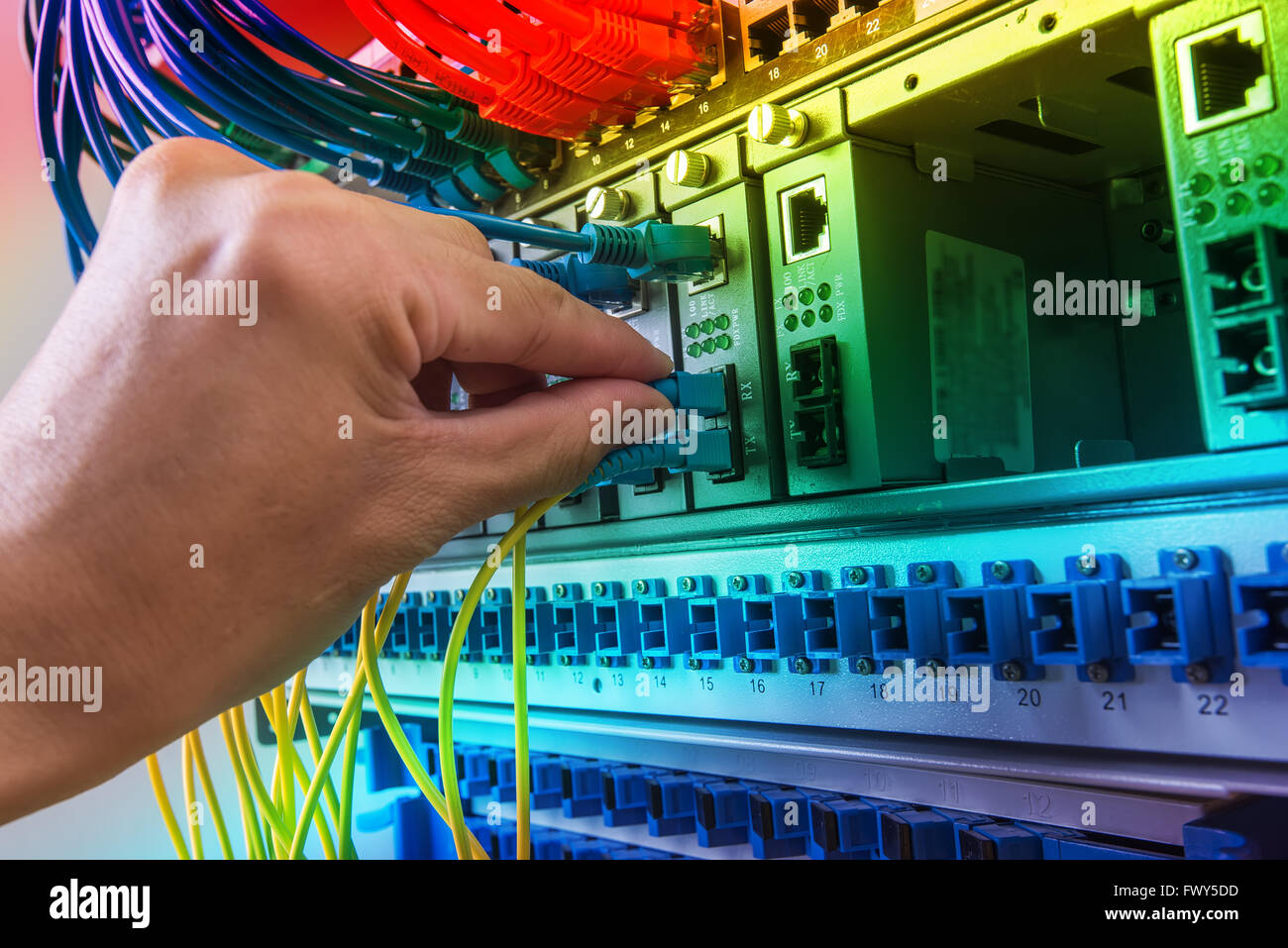 man working in network server room with fiber optic hub for digital ...