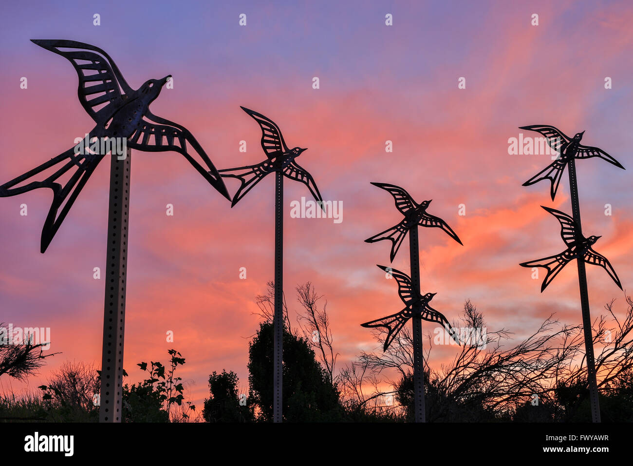 Metal birds flying into the sunset skies Stock Photo - Alamy