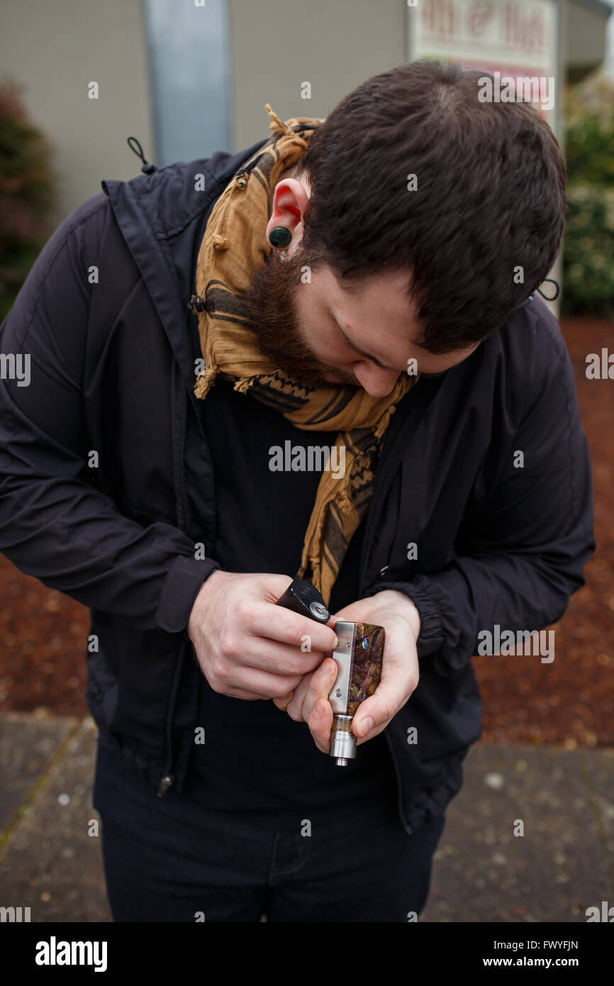 Urban lifestyle portrait of a man vaping in an urban environment with a ...