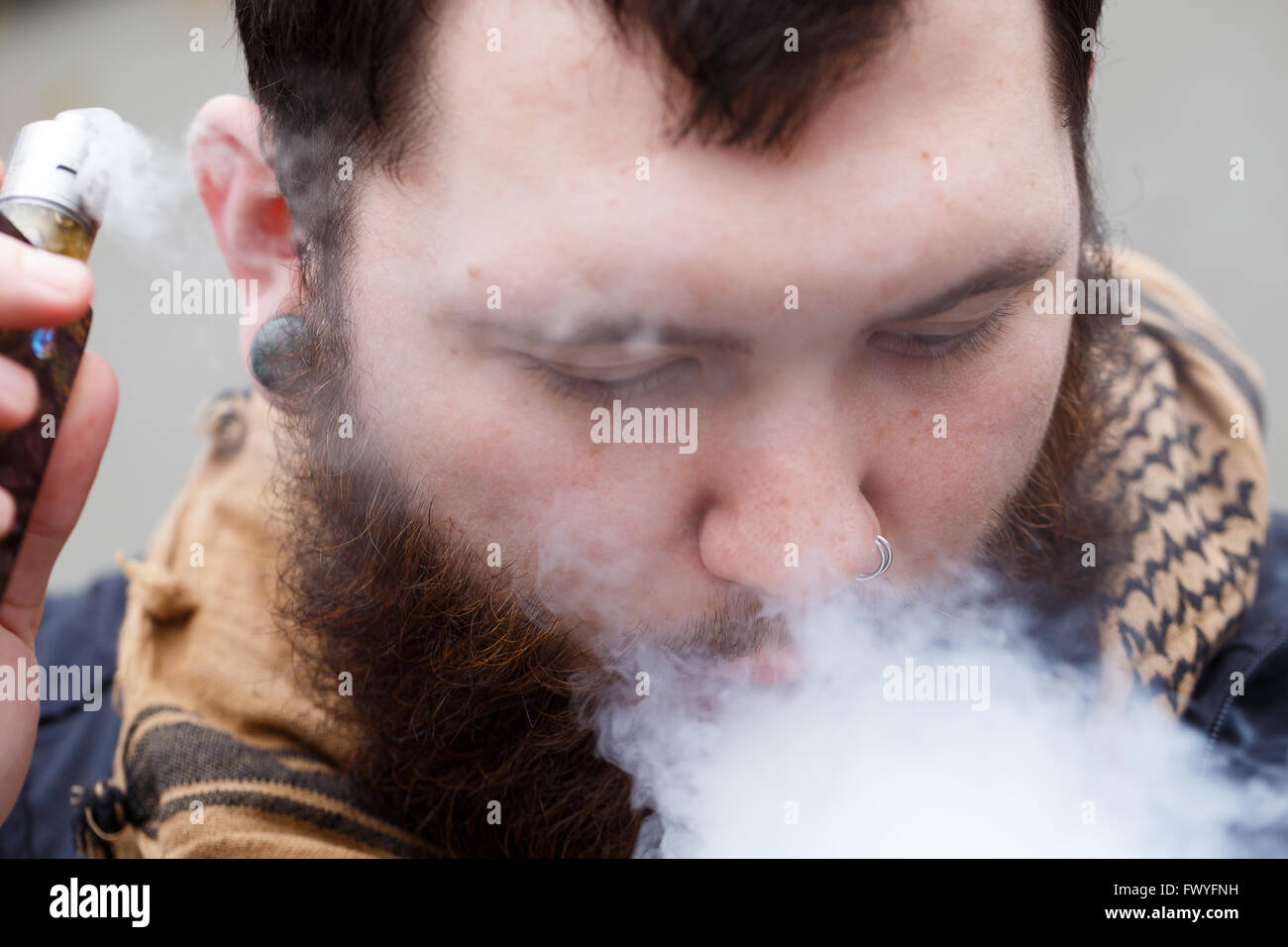 Urban lifestyle portrait of a man vaping in an urban environment with a ...
