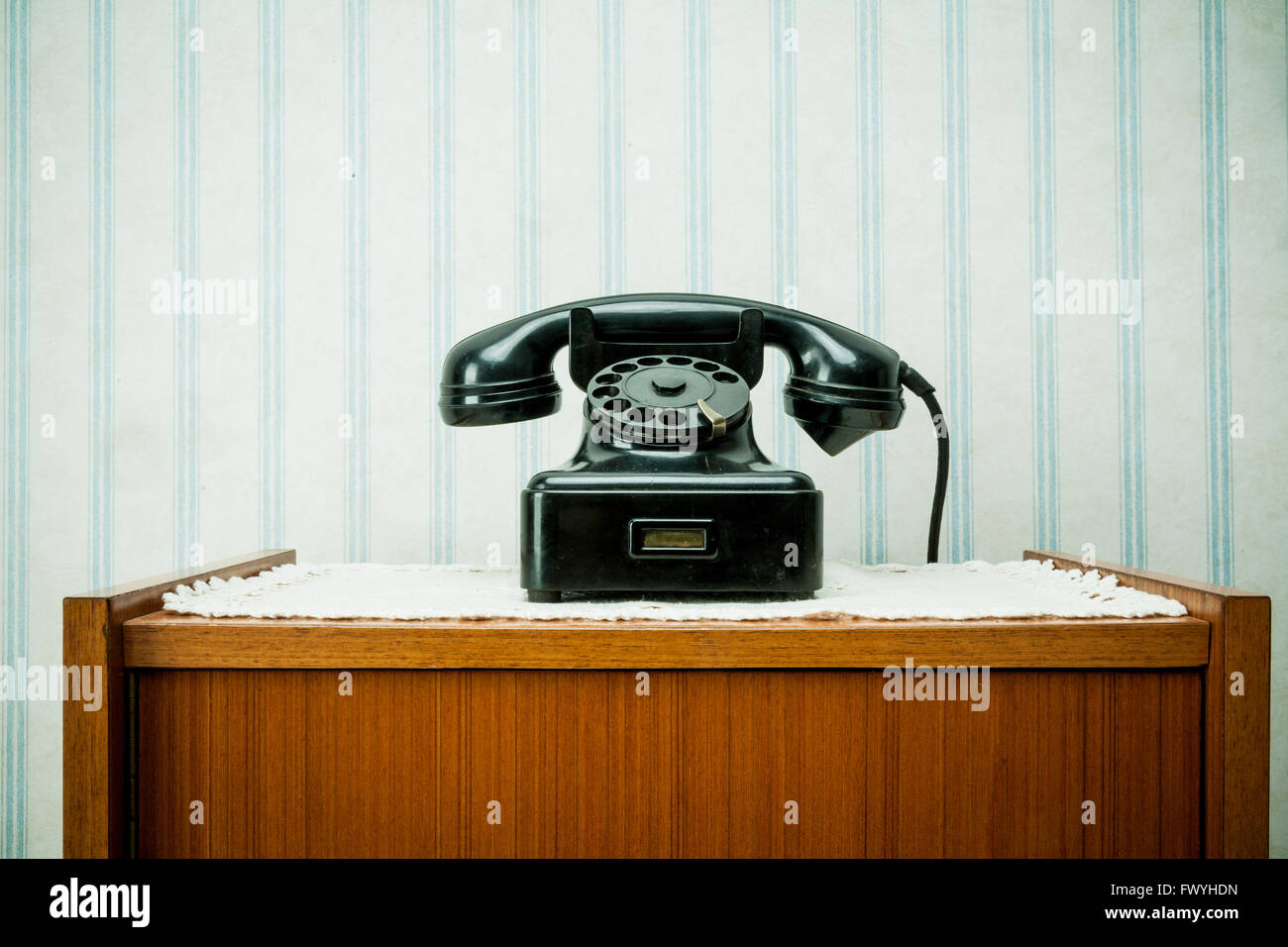 old-style image of a vintage telephone on a night table over a doily ...