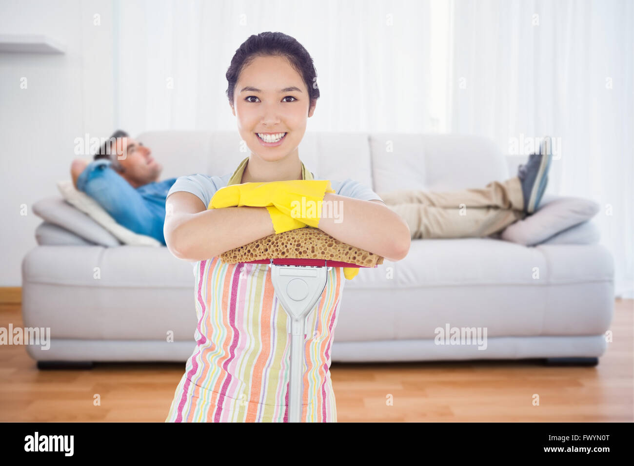 Composite image of smiling woman leaning on mop Stock Photo - Alamy
