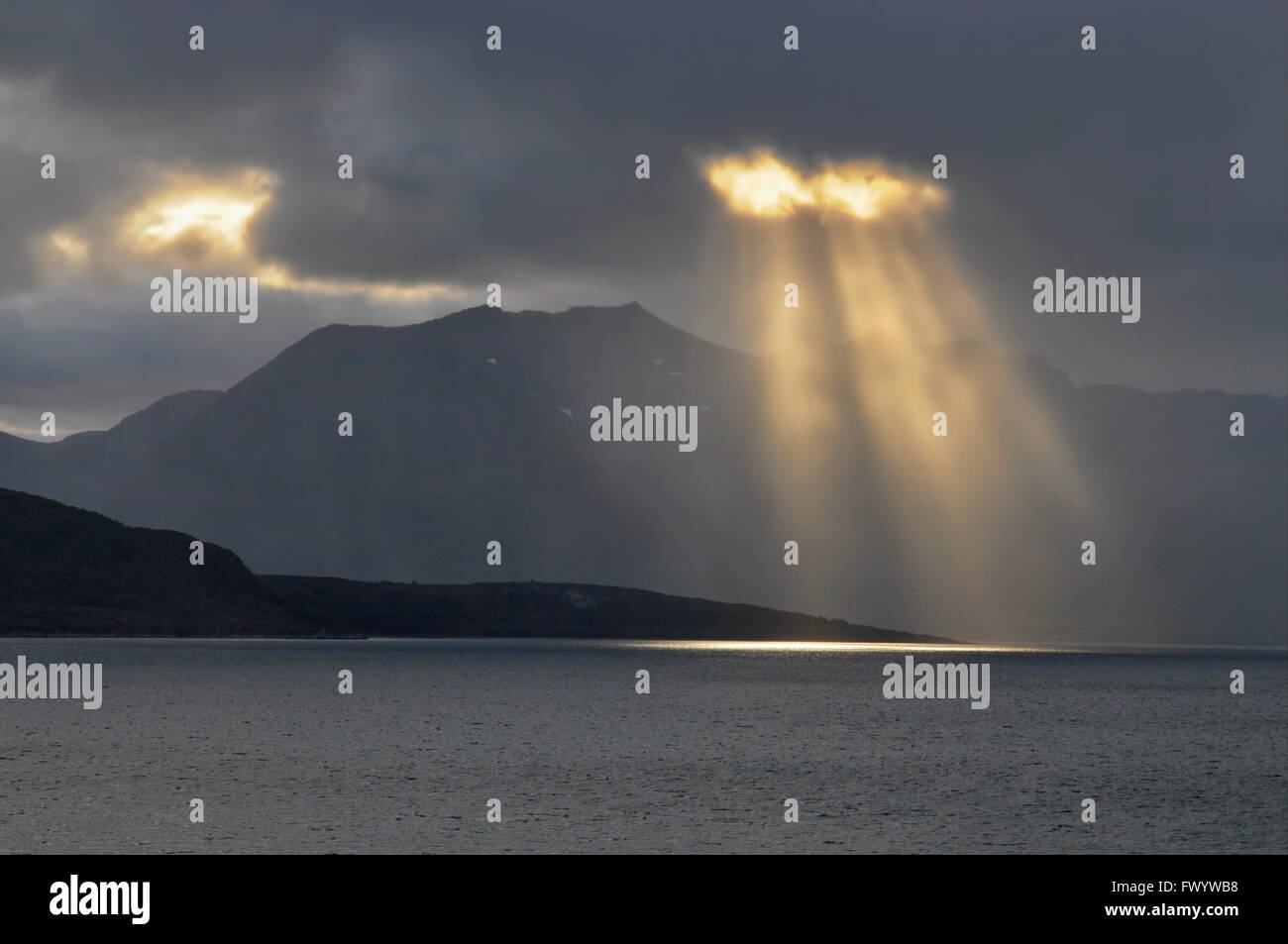Sun rays are breaking through thick rain clouds at Kvæfjord on island ...