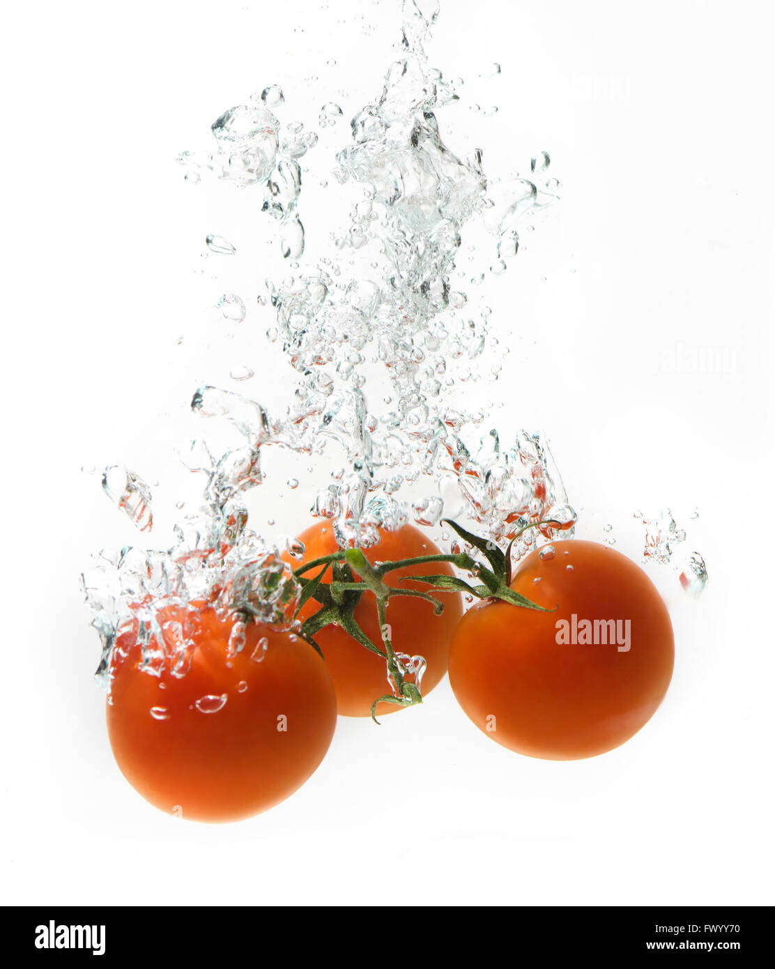 Three tomatoes falling into water - studio isolated Stock Photo - Alamy