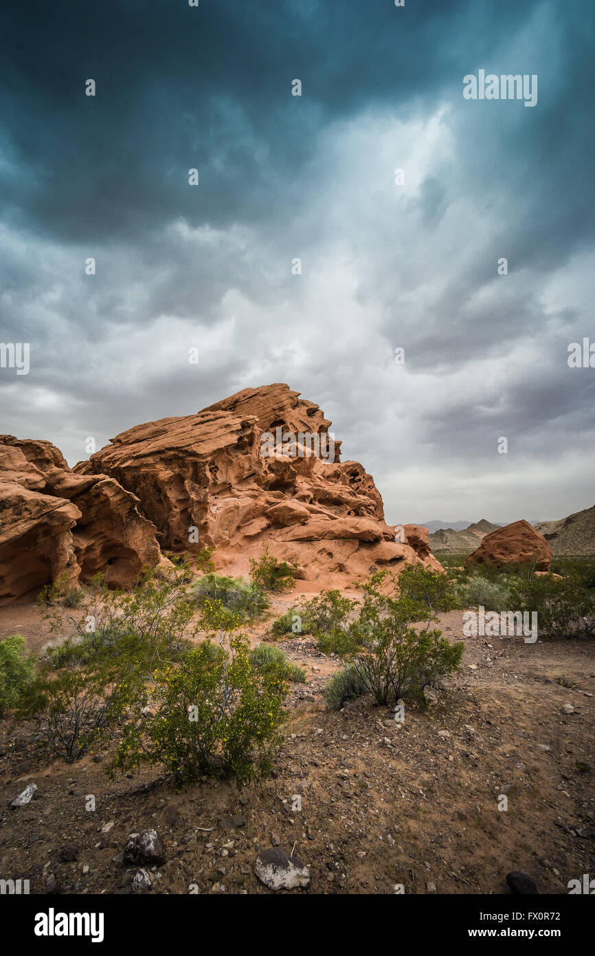Red sandstone rock outcrop against the dark gray of a stormy Nevada sky ...
