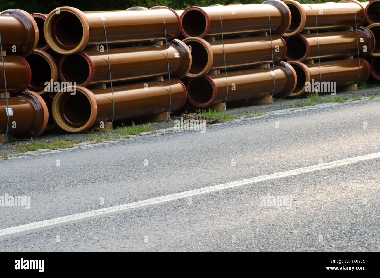 Stacks of pipes next to asphalt road Stock Photo - Alamy
