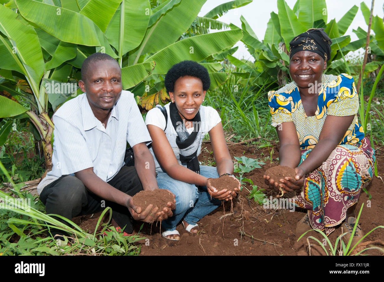 Rwandan agricultural experts looking at soil with a local farmer and ...