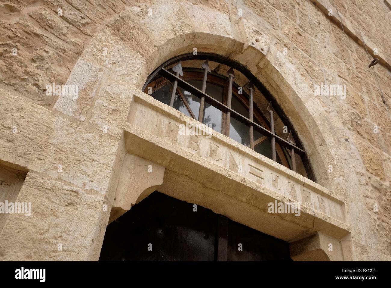 A semi-circular upper window, with a stylized iron grille at the ...