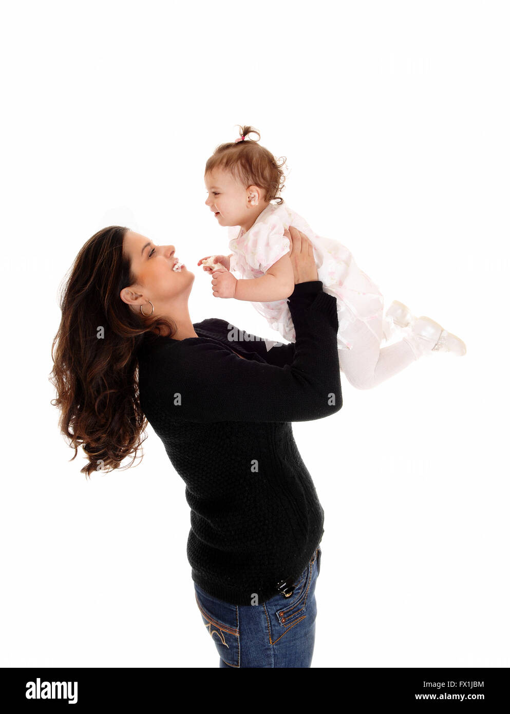A mother lifting up her daughter baby, standing isolated for white ...