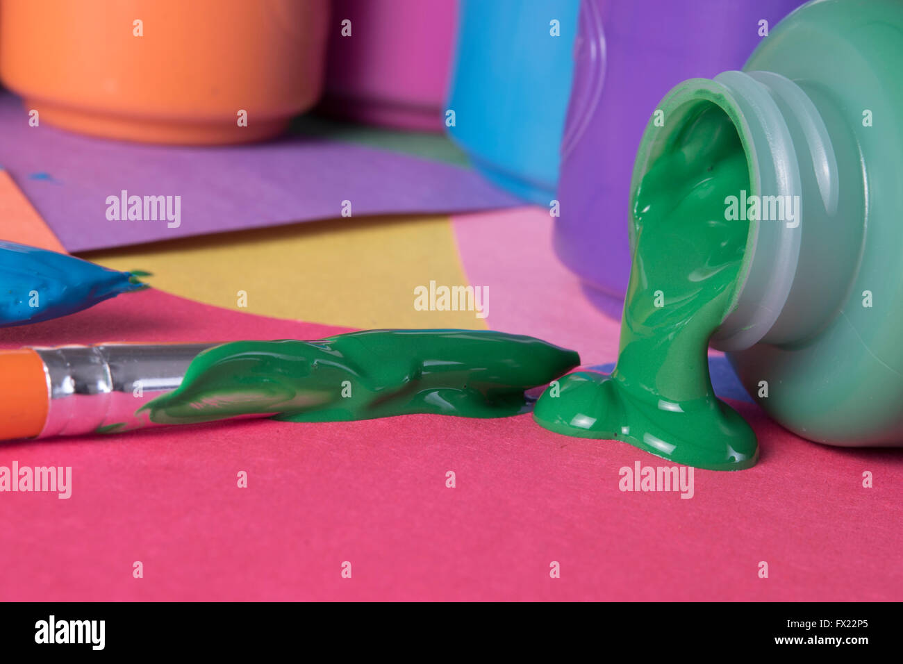 green paint spilling from container, blue, orange and red colors in ...
