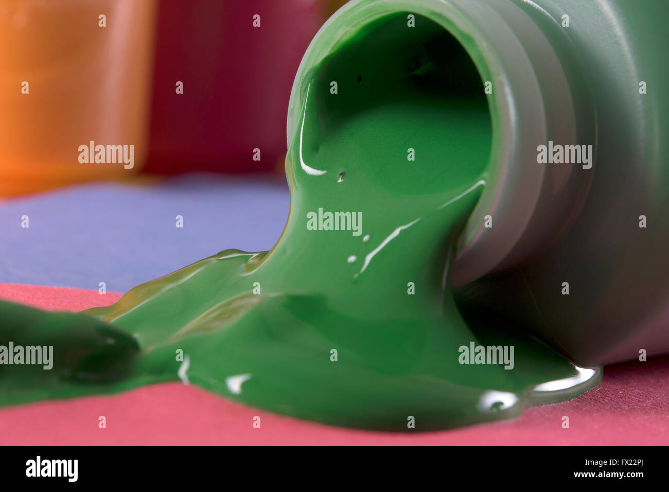 green paint spilling from container, blue, orange and red colors in ...