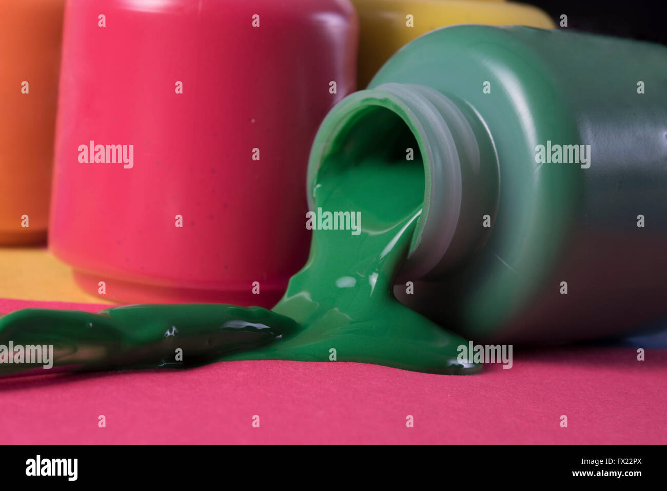 green paint spilling from container, blue, orange and red colors in ...