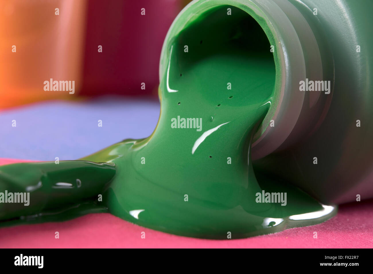 green paint spilling from container, blue, orange and red colors in ...