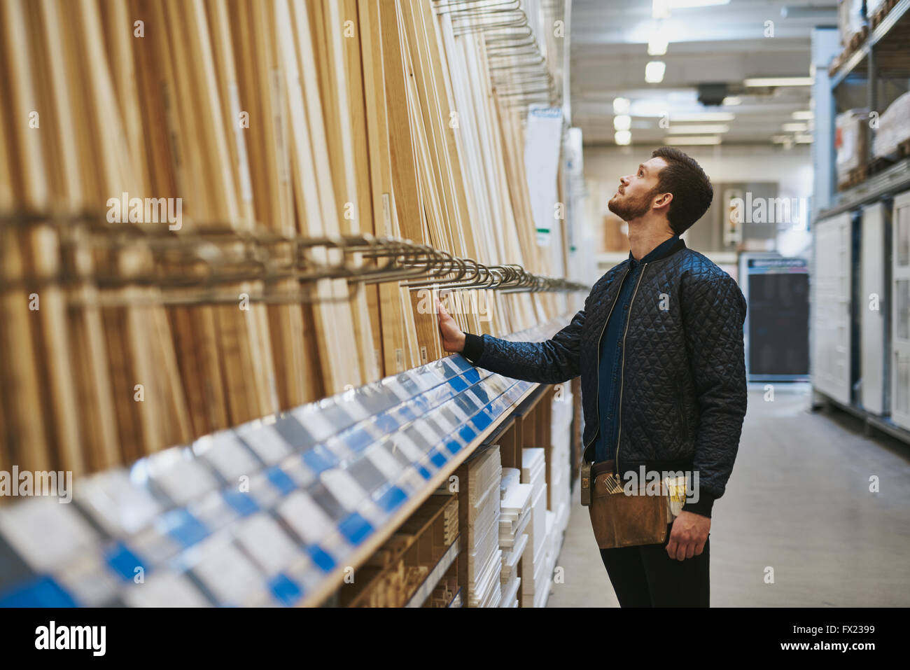 Carpenter selecting wood in a hardware store or warehouse standing ...