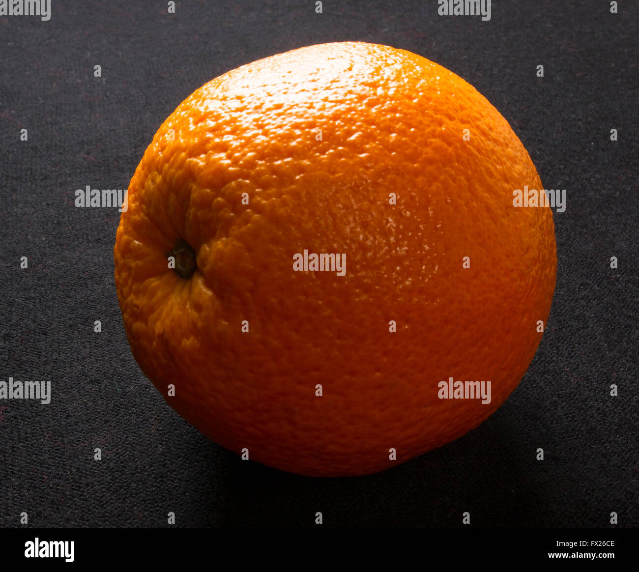 The Big Orange on the textile black background Stock Photo - Alamy