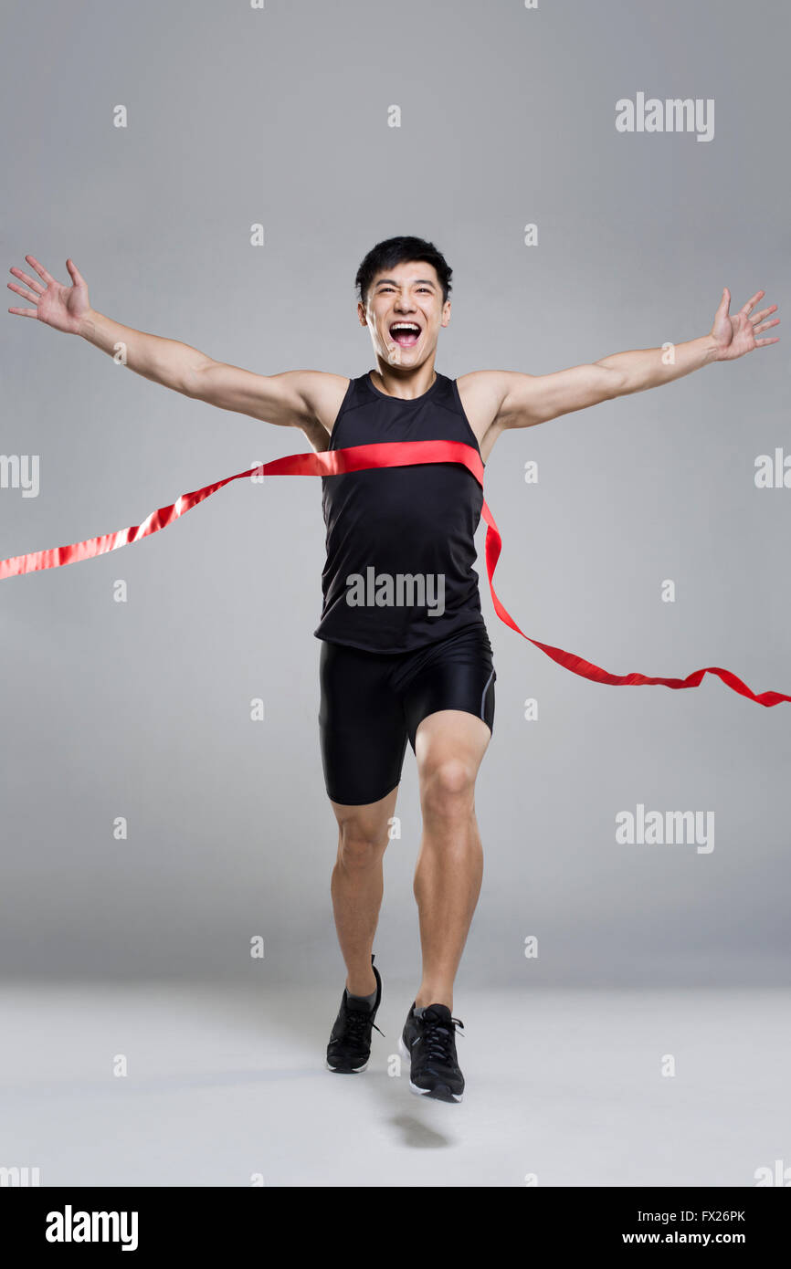 Male athlete reaching the finish line Stock Photo - Alamy